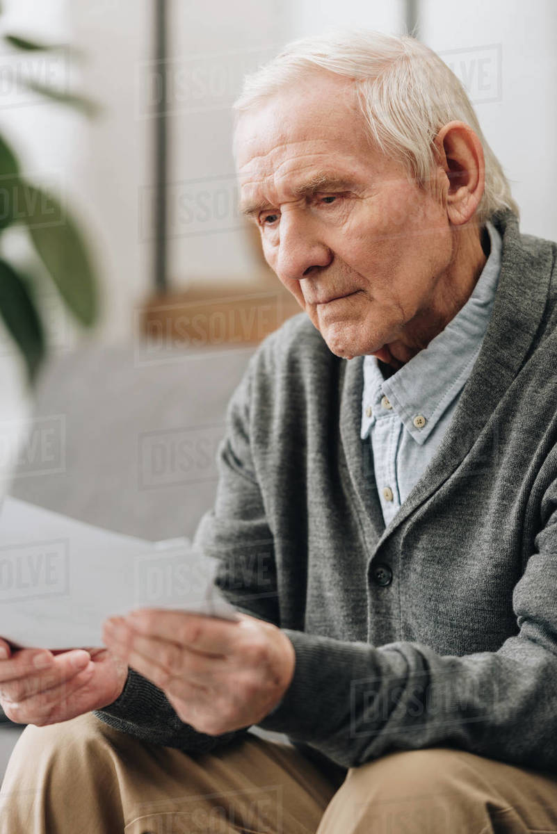 Retired man with grey hair looking at photos at home - Royalty-free ...