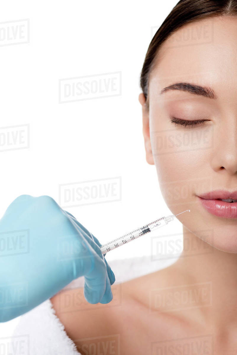 Cropped view of doctor in latex glove giving lip injection with syringe ...