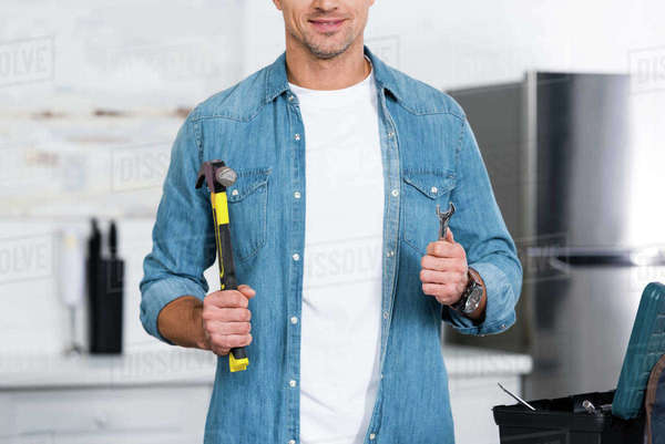 Cropped view of smiling man holding hammer and wrench in hands ...