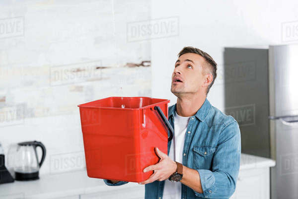 Handsome man holding plastic bucket and looking at ceiling - Royalty ...