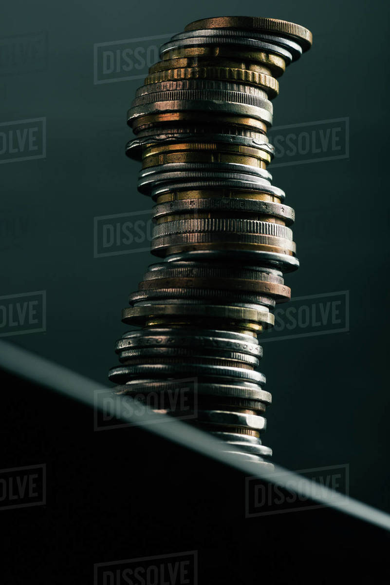 Close up view of stack of different coins standing on edge of table ...