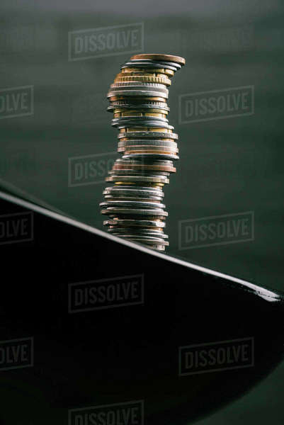Close up view of stack of different coins standing on edge of table ...