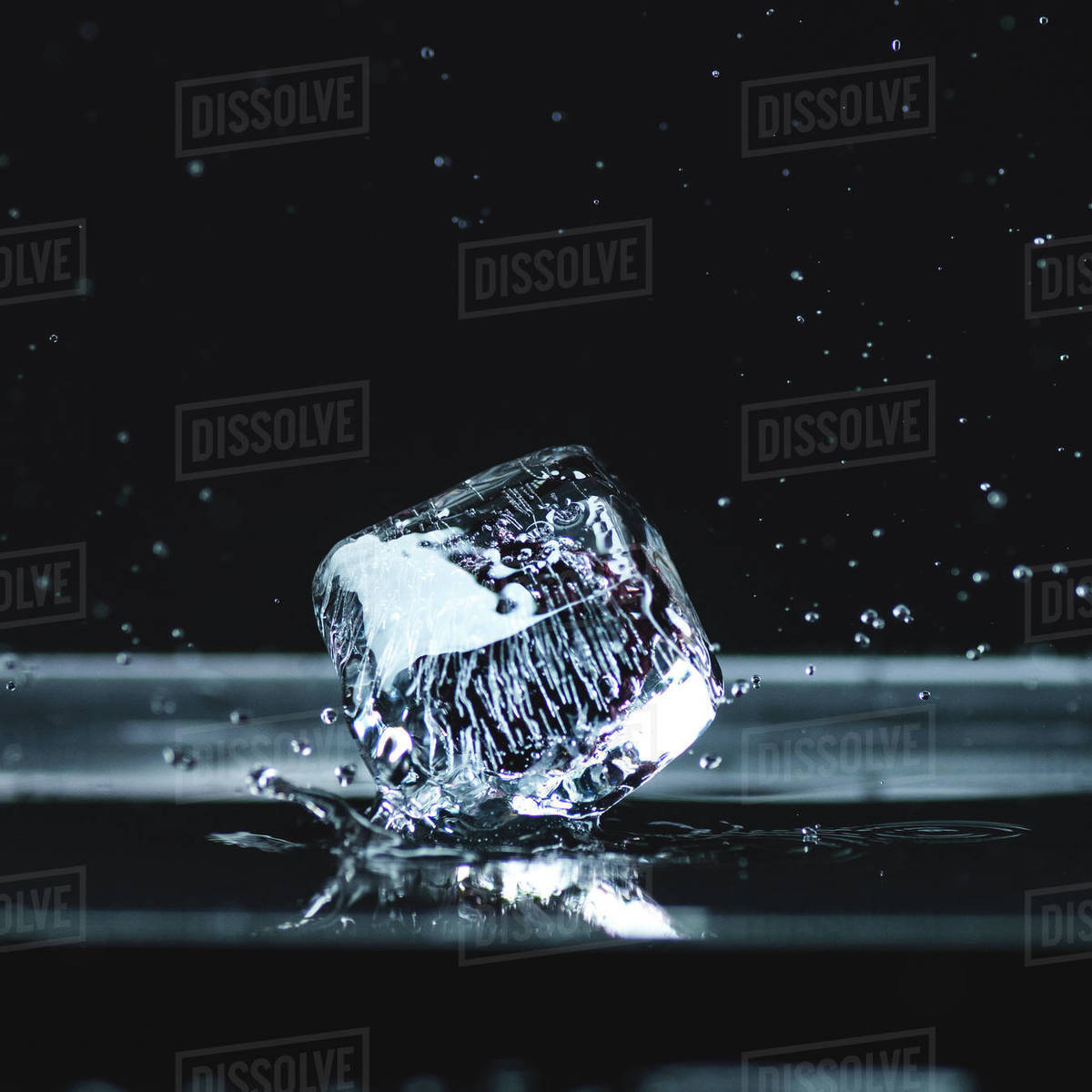 Close-up view of shiny melting ice cube with water drops on black ...