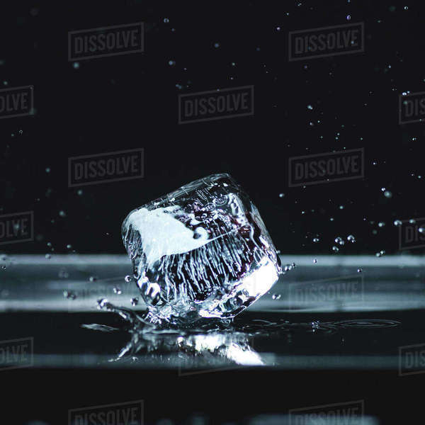 Close-up view of shiny melting ice cube with water drops on black ...
