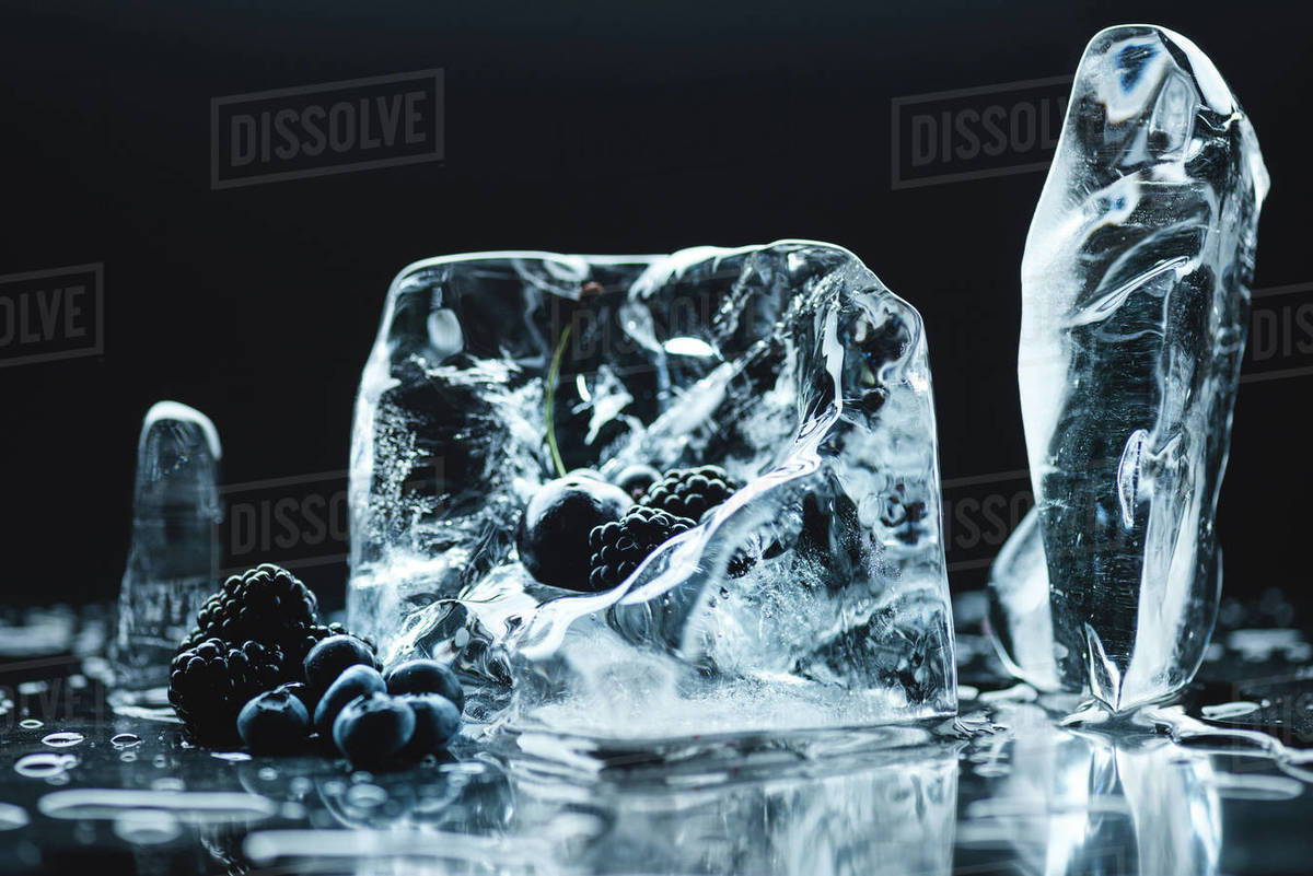 Close-up view of ripe juicy berries and melting ice crystals on black ...