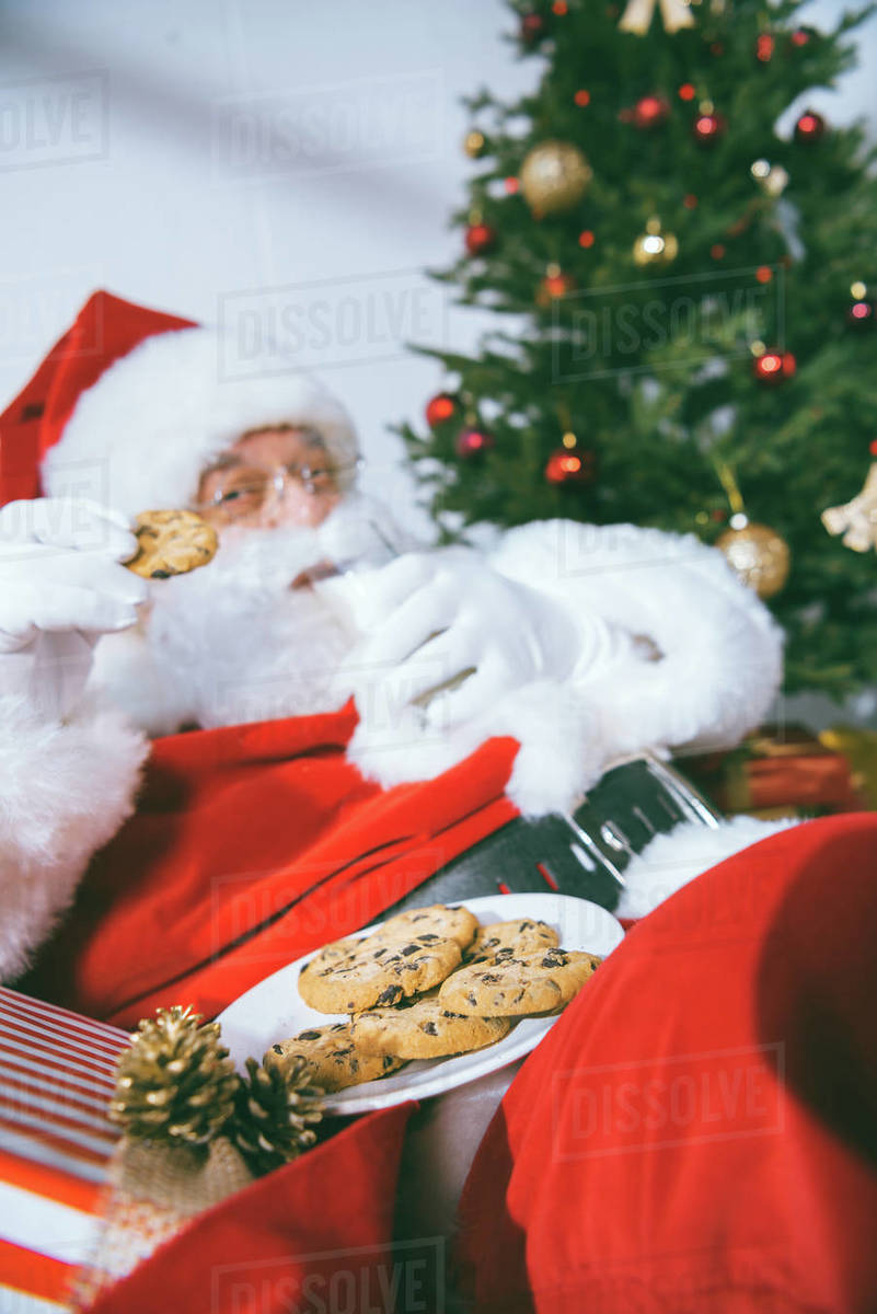 selective focus of santa claus eating cookies and drinking milk ...