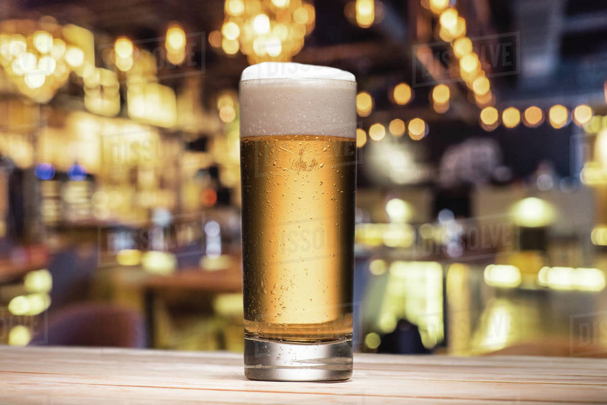 selective focus of mug of beer standing on wooden table in bar ...