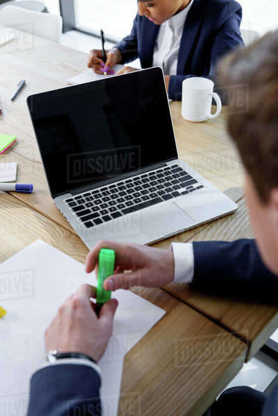 cropped shot of young businessman using laptop with blank screen while ...