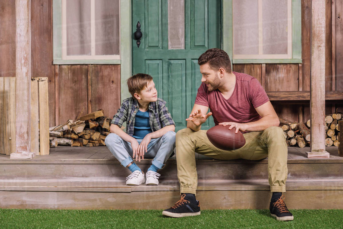 Young father with little son sitting on porch at backyard, dad and son ...