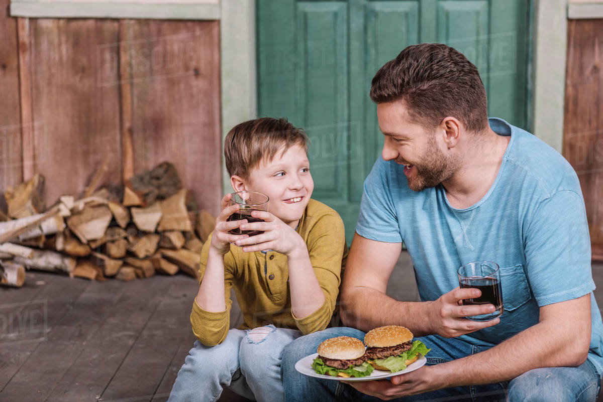 Portrait of happy father and son eating homemade burgers - Stock Photo ...
