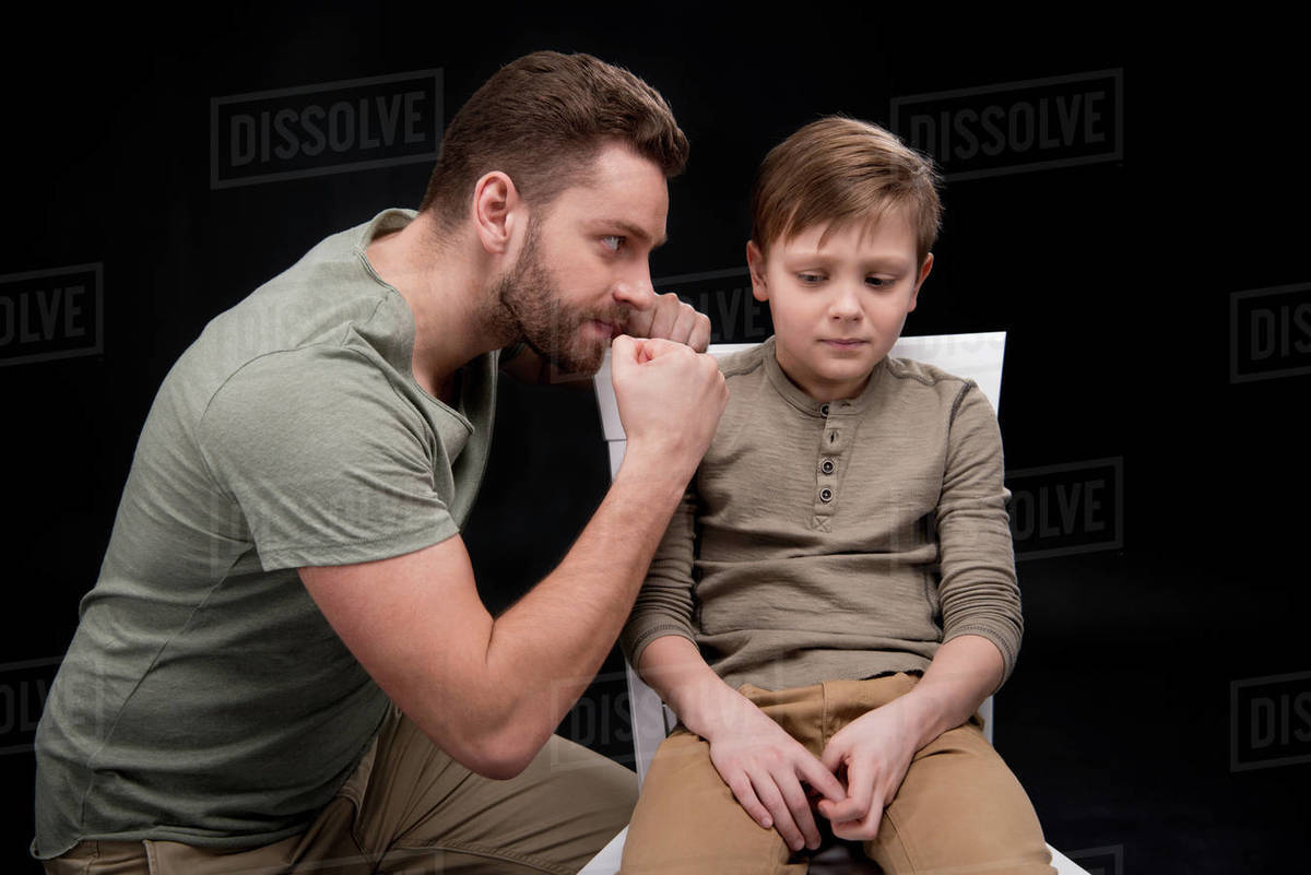 Angry father threatening and gesturing to scared little son sitting on ...