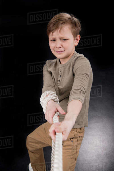 Emotional little boy pulling rope isolated on black - Royalty-free ...