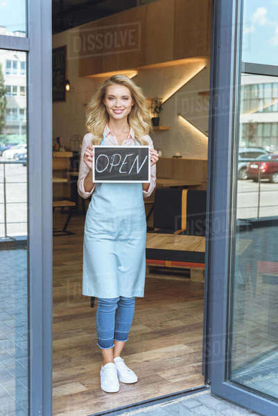 Attractive young waitress holding sign open and smiling at camera ...