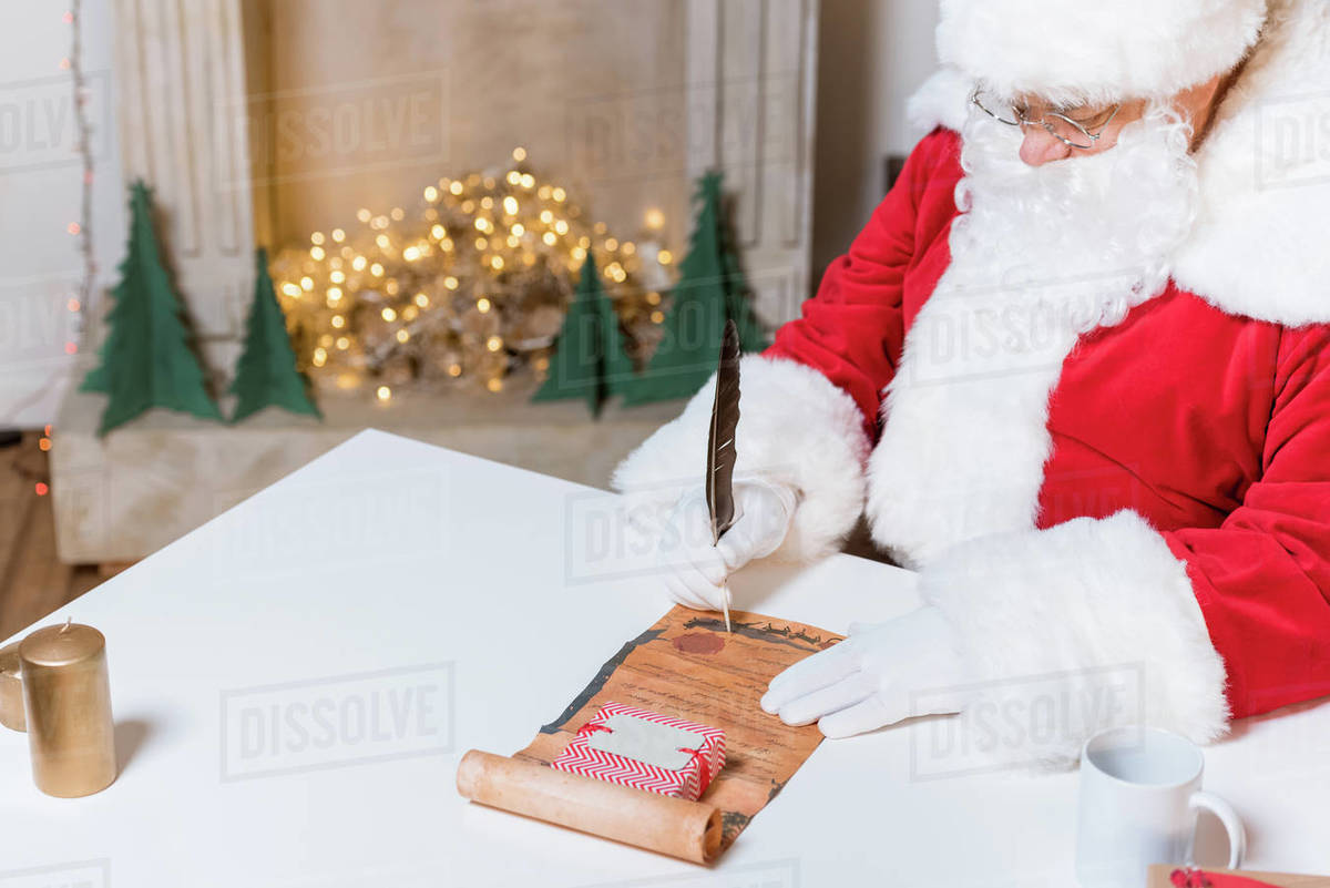 Portrait of Santa Claus signing wish list with feather in hand ...
