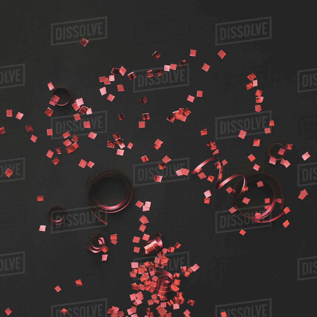 Red confetti on black background for holidays - Stock Photo - Dissolve