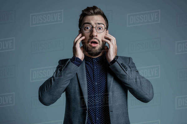 Scared young man in formal suit and glasses looking at camera - Royalty ...