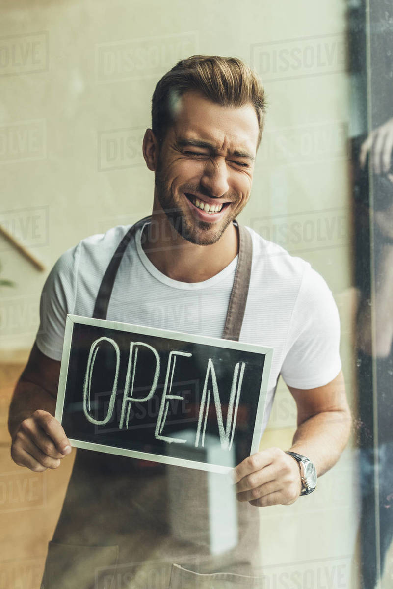 Portrait of smiling waiter holding chalkboard with open word - Royalty ...