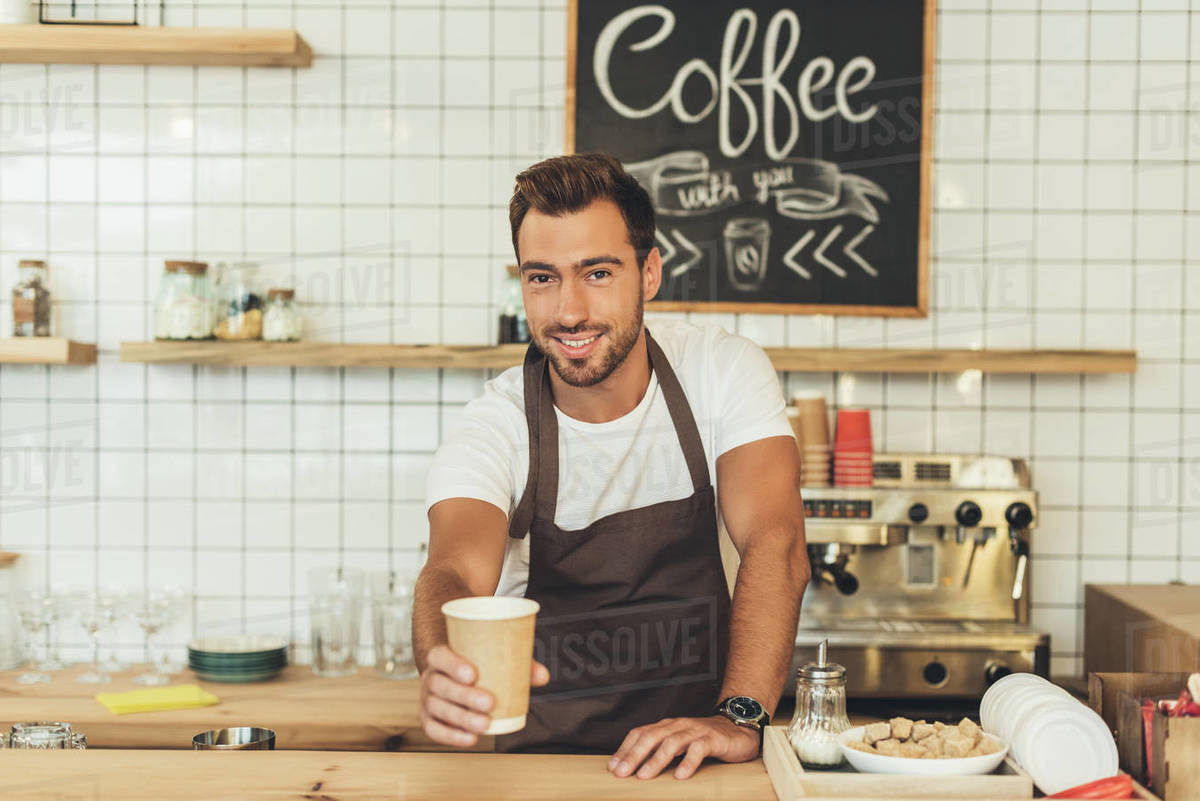 Portrait of smiling barista putting coffee to go on counter in cafe ...