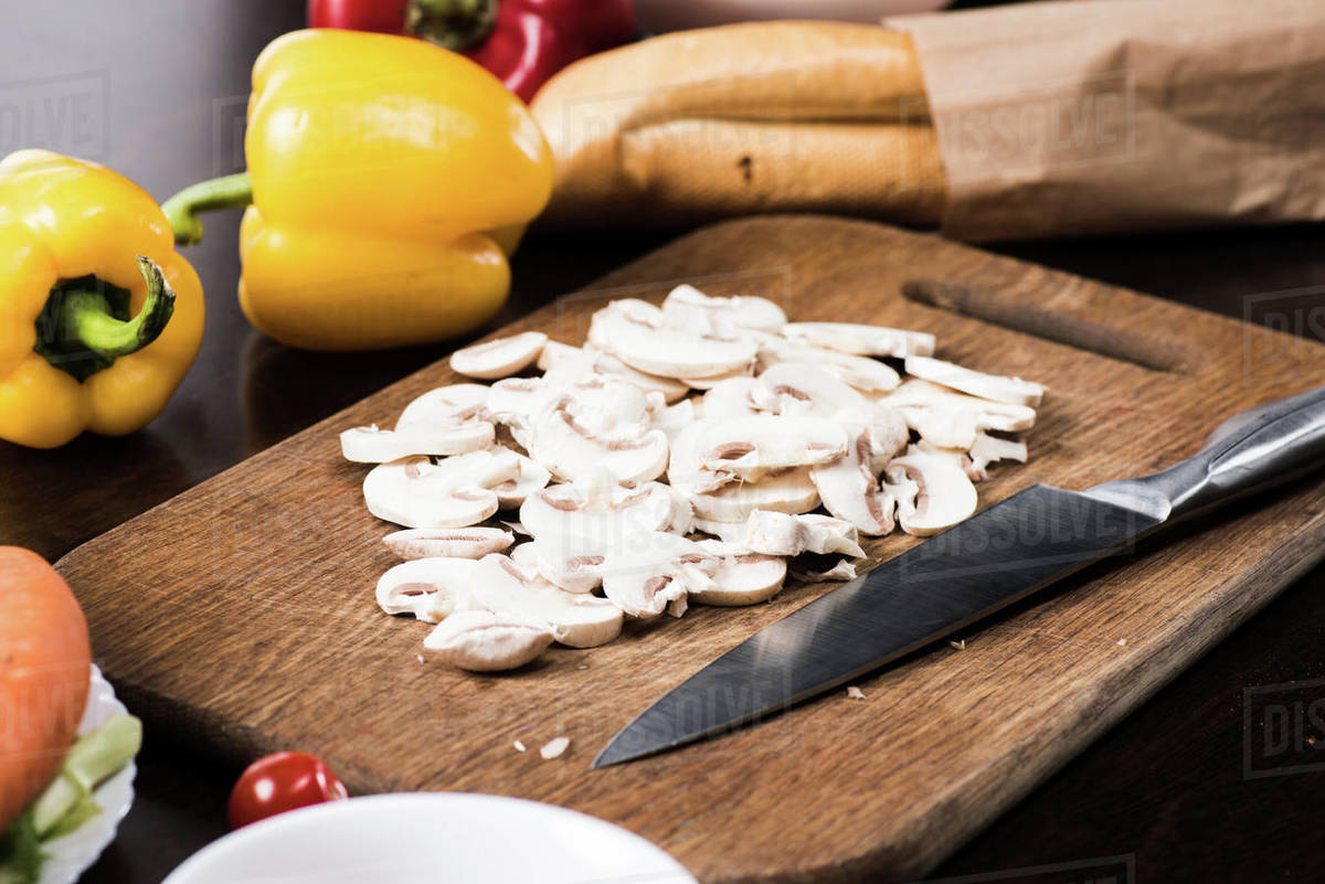 Close up view of cut raw mushrooms on cutting board and knife - Royalty ...