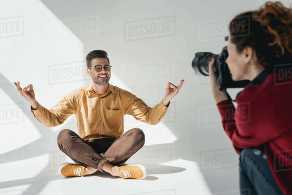 professional female photographer and handsome model in lotus position ...