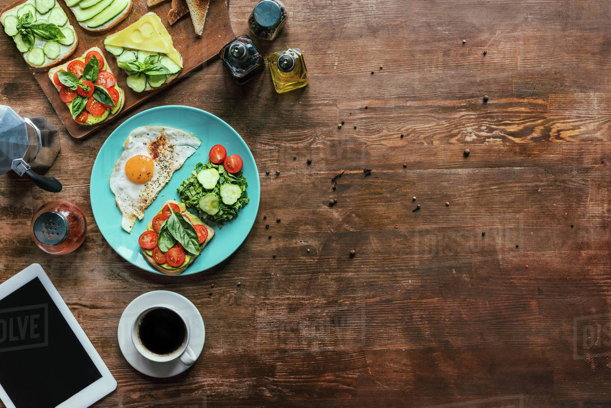 Flat lay with healthy breakfast on plate, cup of coffee and tablet on ...