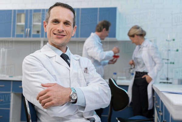 Smiling medical worker in laboratory, sitting with arms crossed and ...