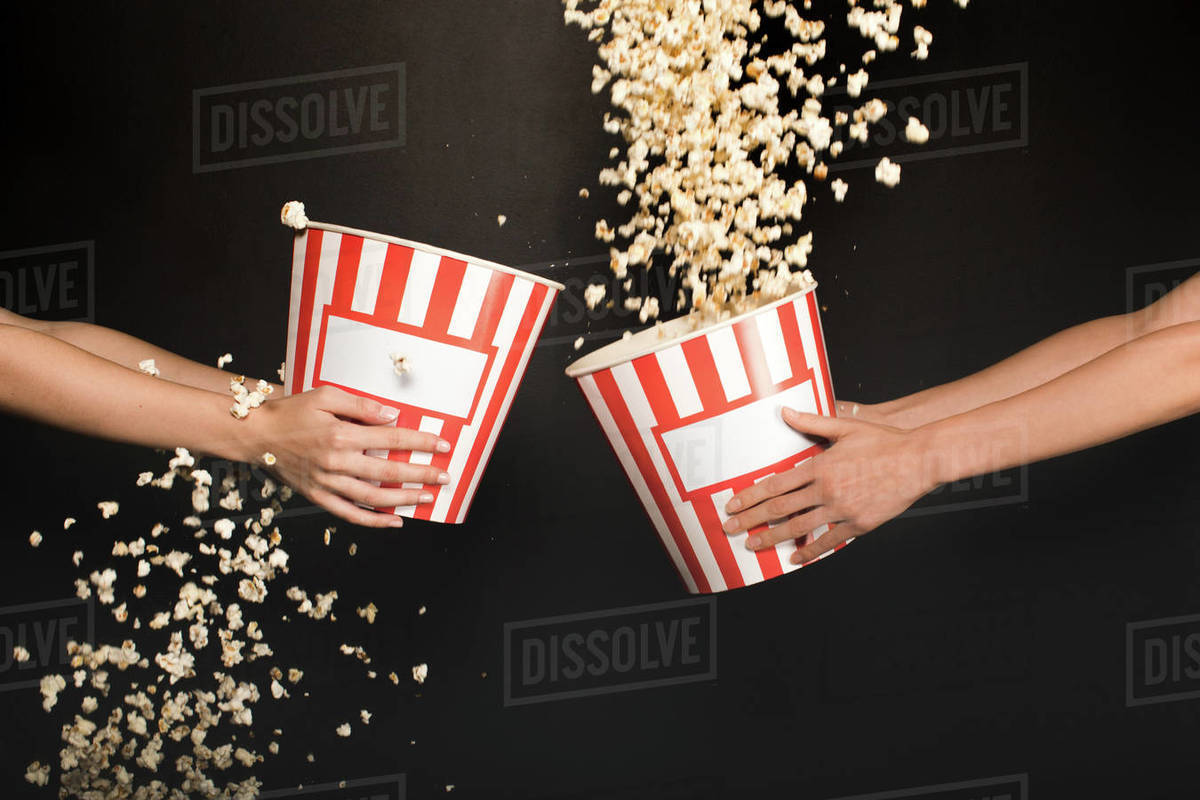 Cropped shot of people spilling out popcorn from buckets isolated on ...