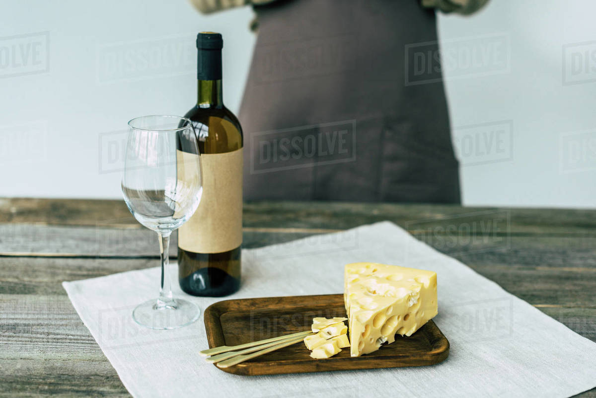 Taster standing at table with bottle of white wine, empty glass and ...