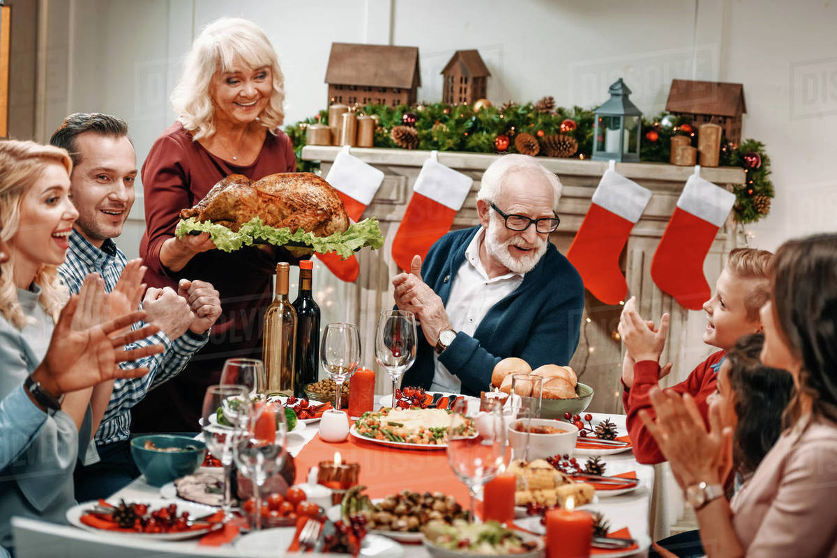 Grandmother holding Christmas turkey while family clapping - Royalty ...