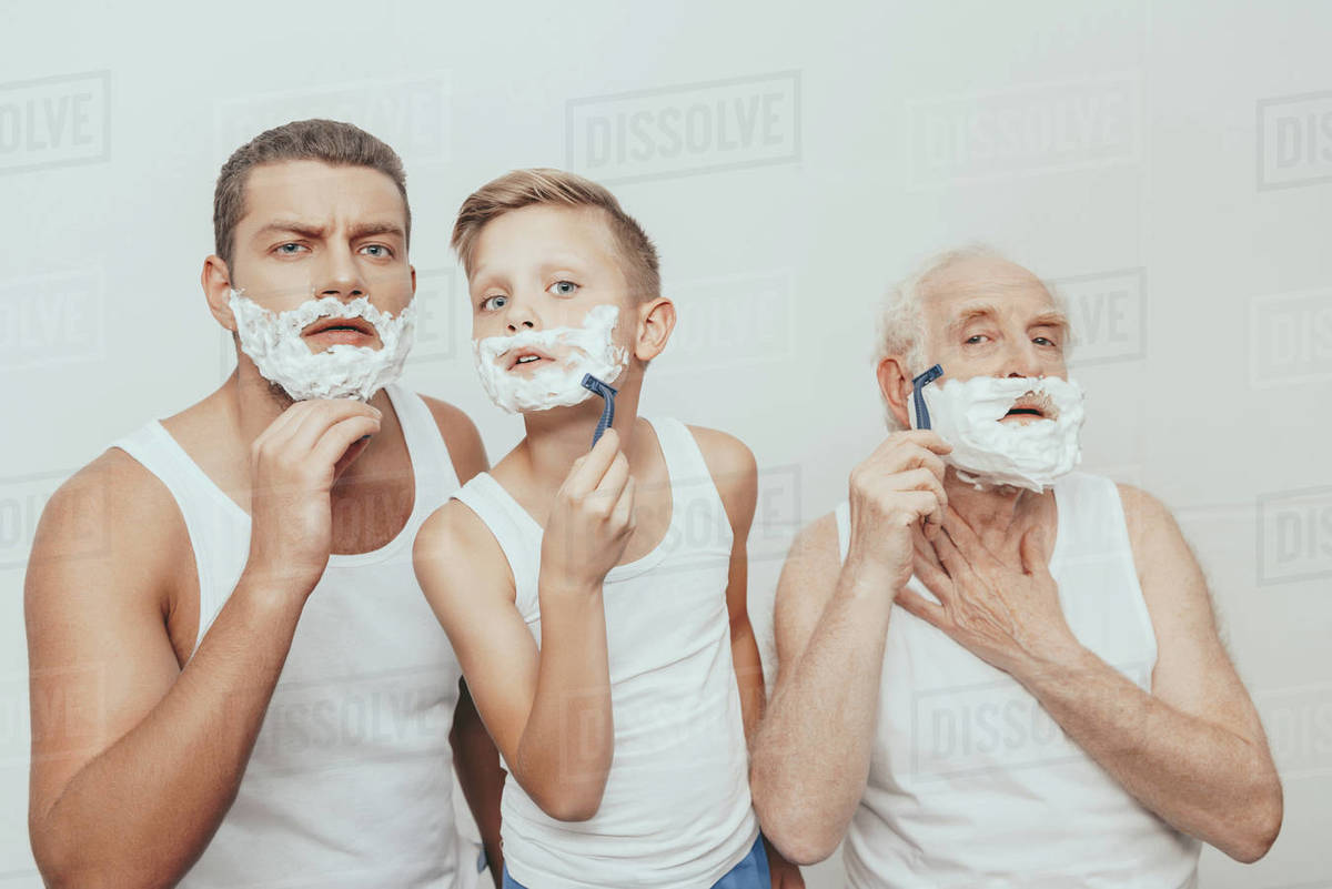 Father, son and grandfather standing with shaving cream on their faces ...