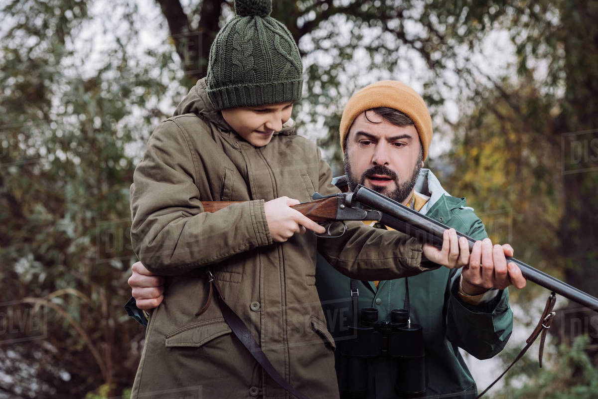 Handsome father showing son how to load gun for hunt - Royalty-free ...