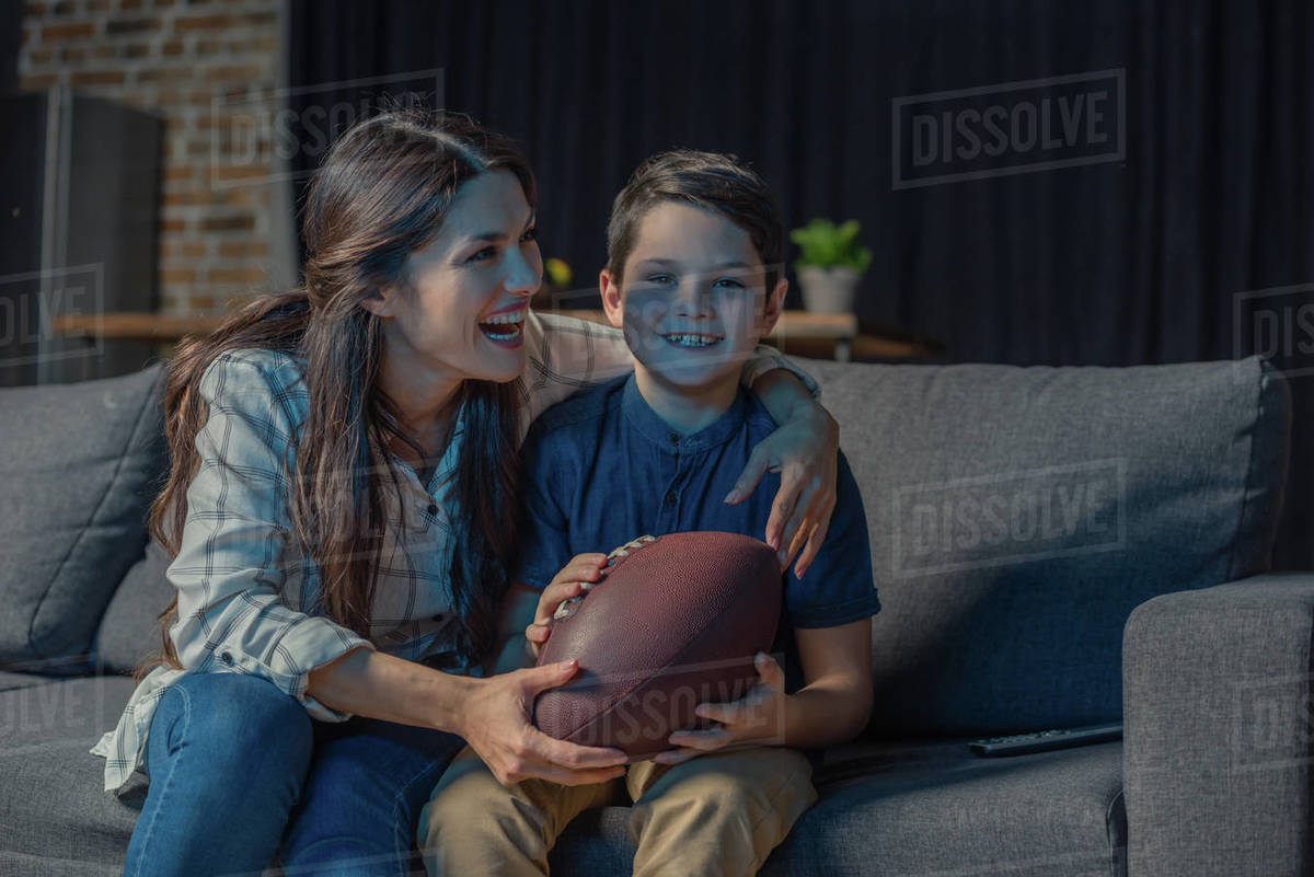 Little Son And His Beautiful Mother Laughing While Sitting On Couch And