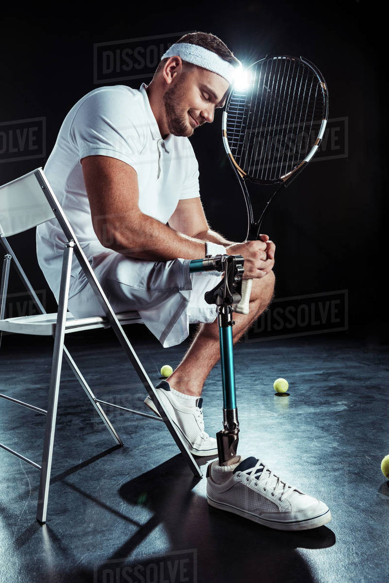 Side view of tennis player with tennis racket resting on chair ...