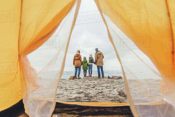 family standing together on seashore and looking at sea - Royalty-free ...
