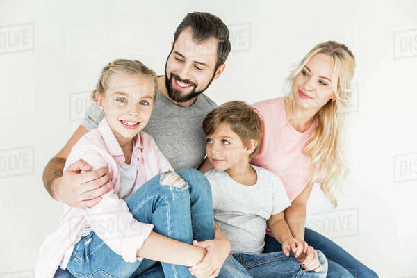 Happy young family with two kids sitting together isolated on white ...