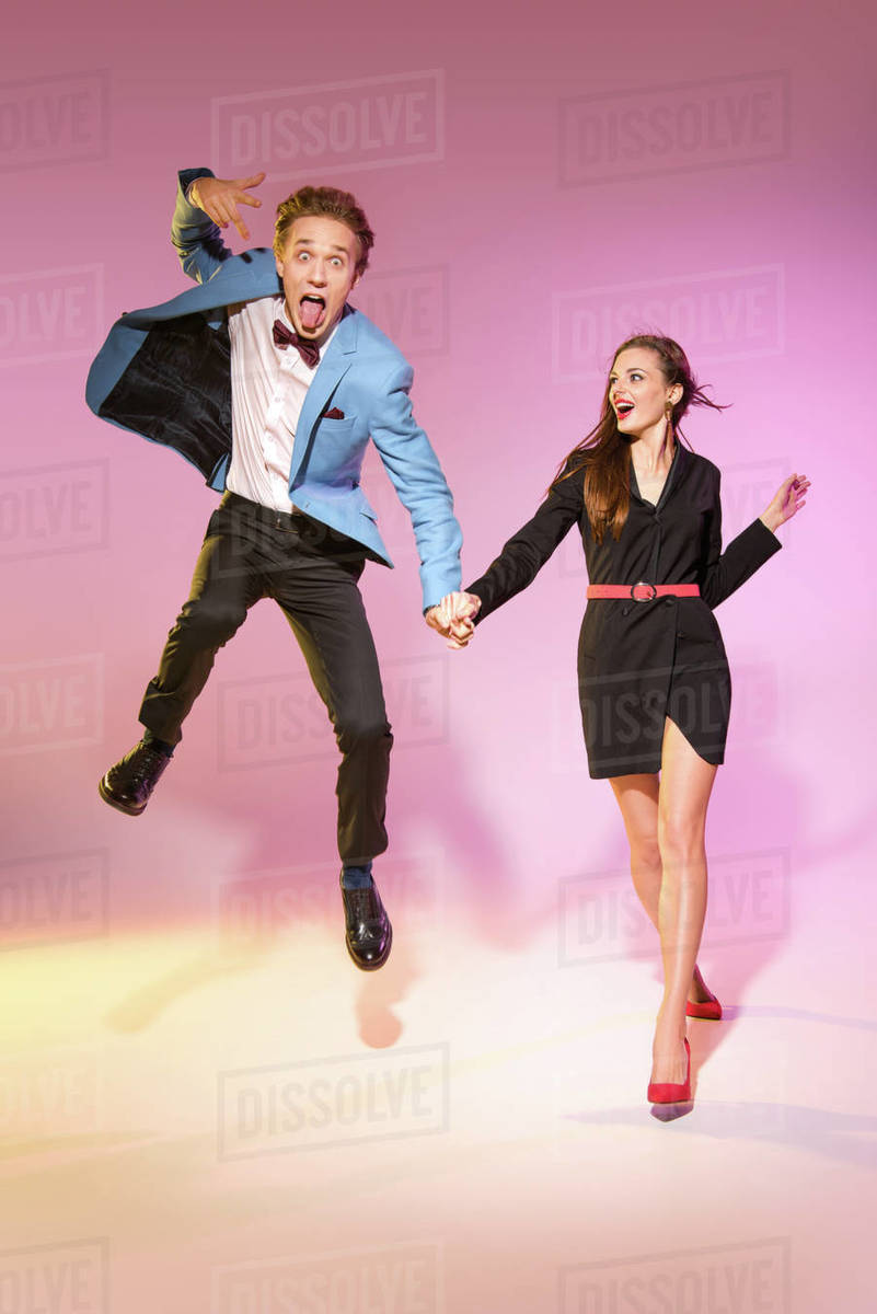 Stylish happy couple hugging and jumping on pink - Royalty-free Stock ...