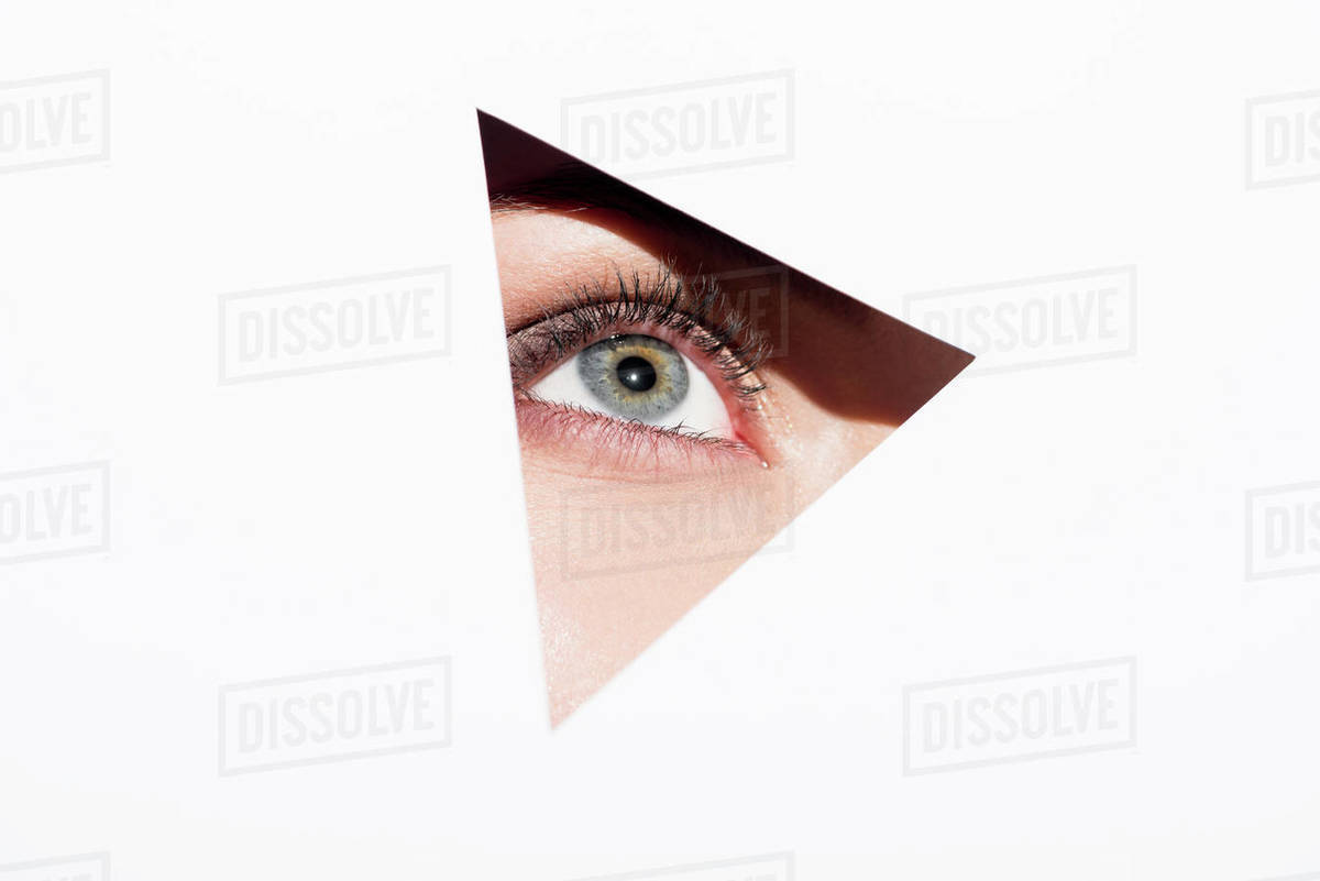 Close-up shot of woman looking out of hole with one eye isolated on ...