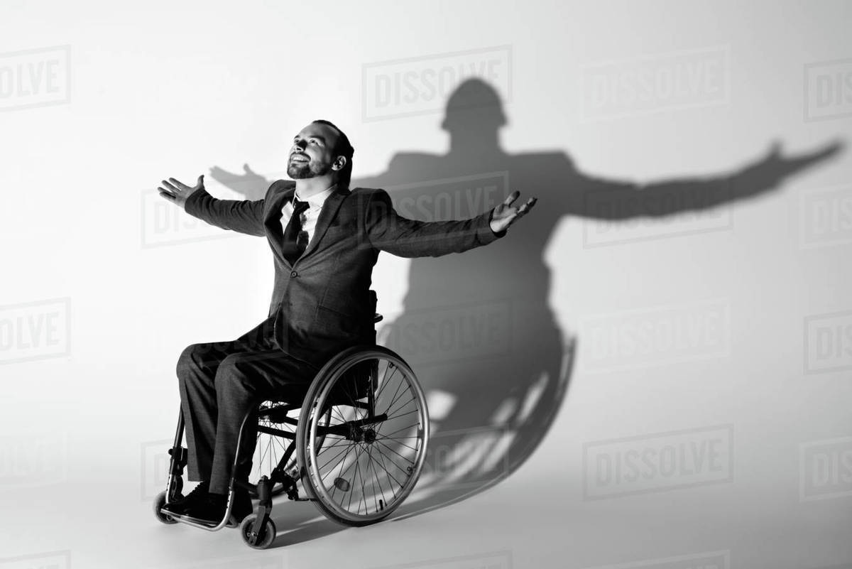 Cheerful businessman in suit sitting in wheelchair gesturing with ...