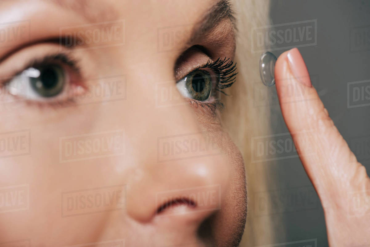 Close-up view of woman applying contact lens isolated on grey - Royalty ...