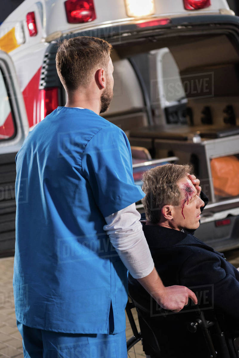 Paramedic moving injured mature man on wheelchair to ambulance - Stock ...