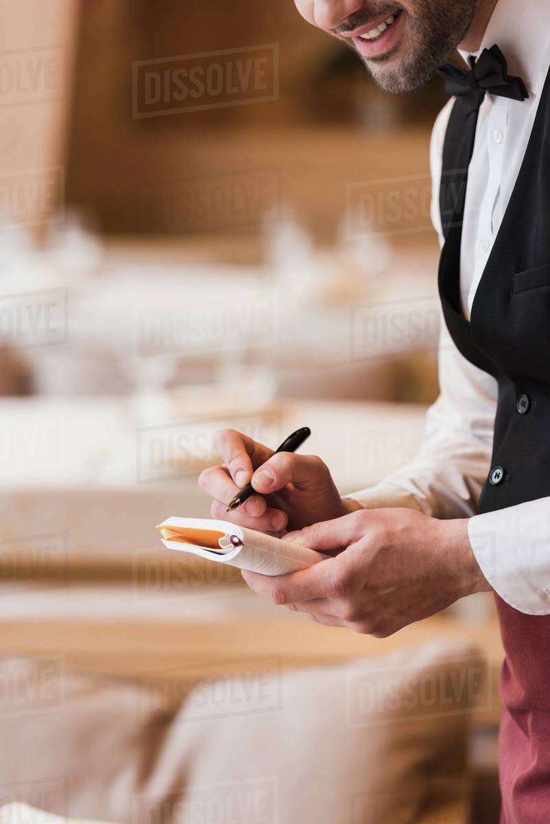 Cropped image of smiling waiter writing down the order - Stock Photo ...