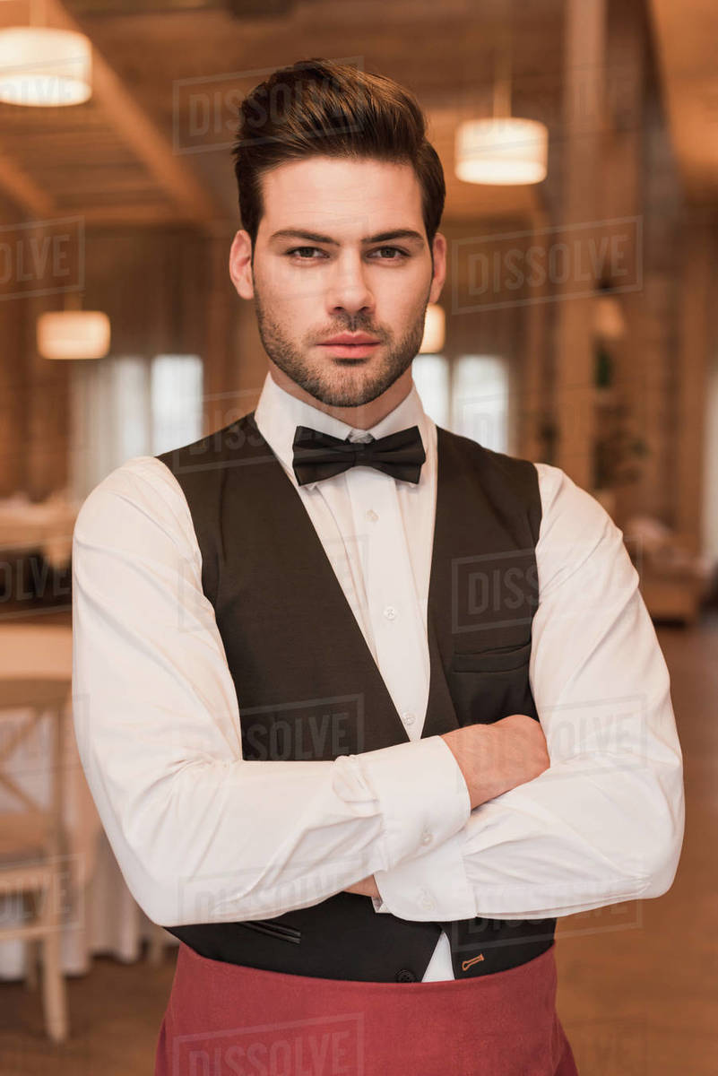 Serious handsome waiter with crossed hands looking at camera - Stock ...