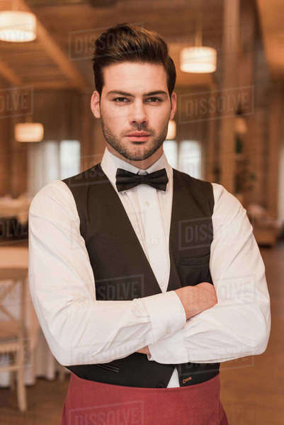 Serious handsome waiter with crossed hands looking at camera - Stock ...