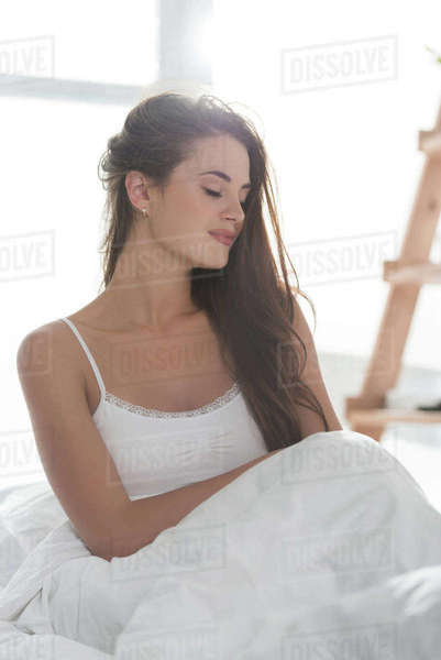 Sleepy young woman relaxing in bed in morning - Stock Photo - Dissolve