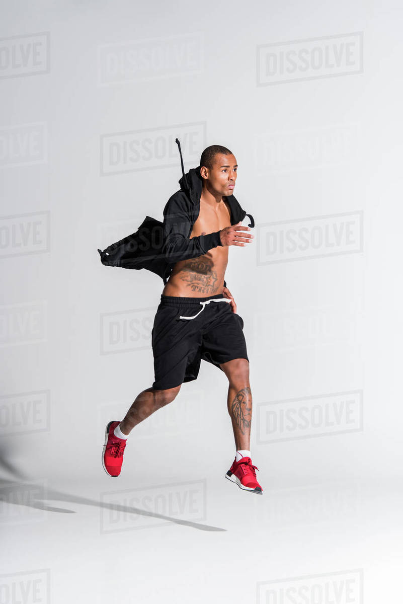 Full length view of young african american sportsman running on grey ...