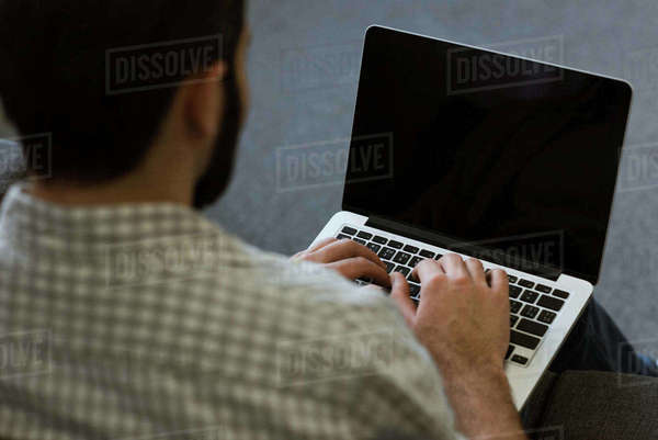 Back view of man sitting on couch and using laptop - Royalty-free Stock ...