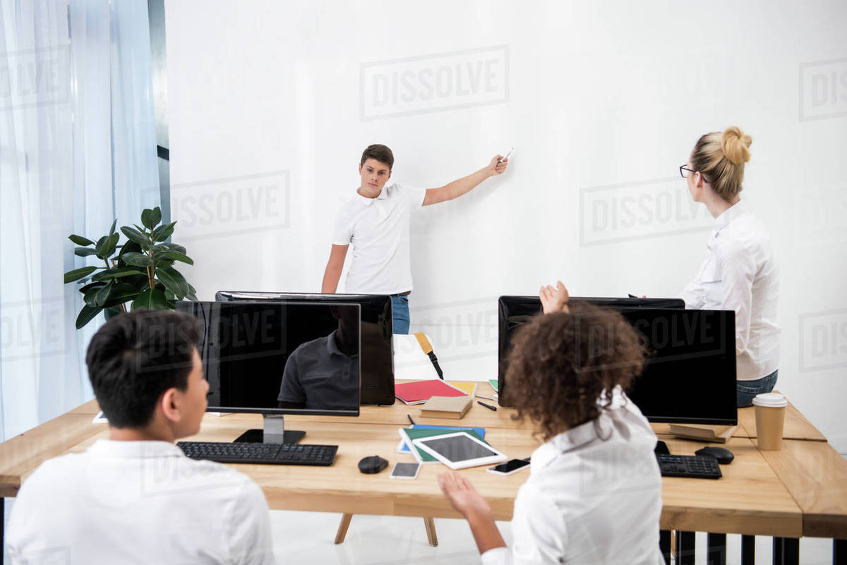 Young teenager pointing on white board in classroom with students ...