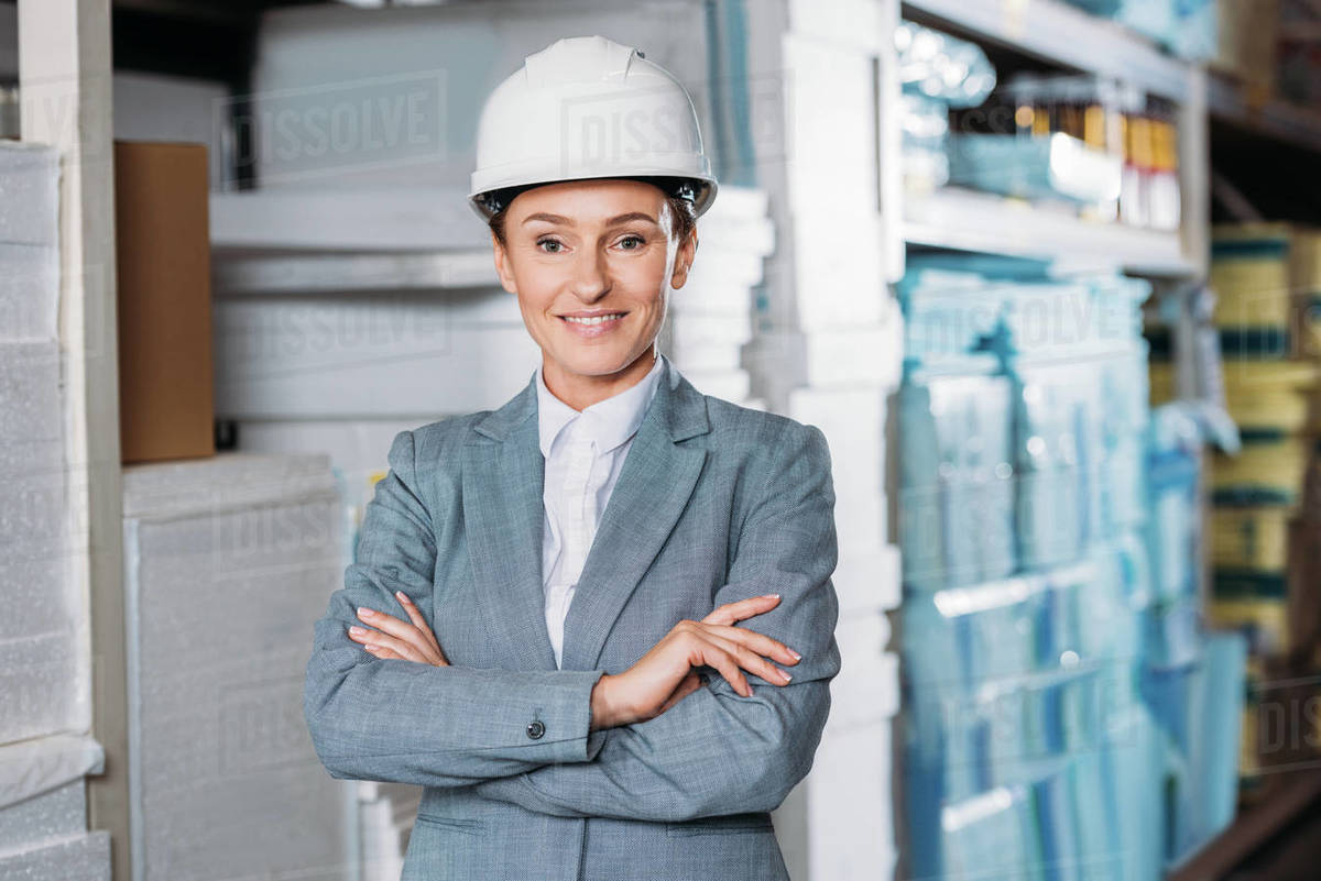 Female inspector in helmet posing with crossed arms in shipping stock ...