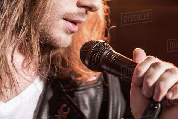 Cropped shot of young male singer with microphone on stage - Royalty ...