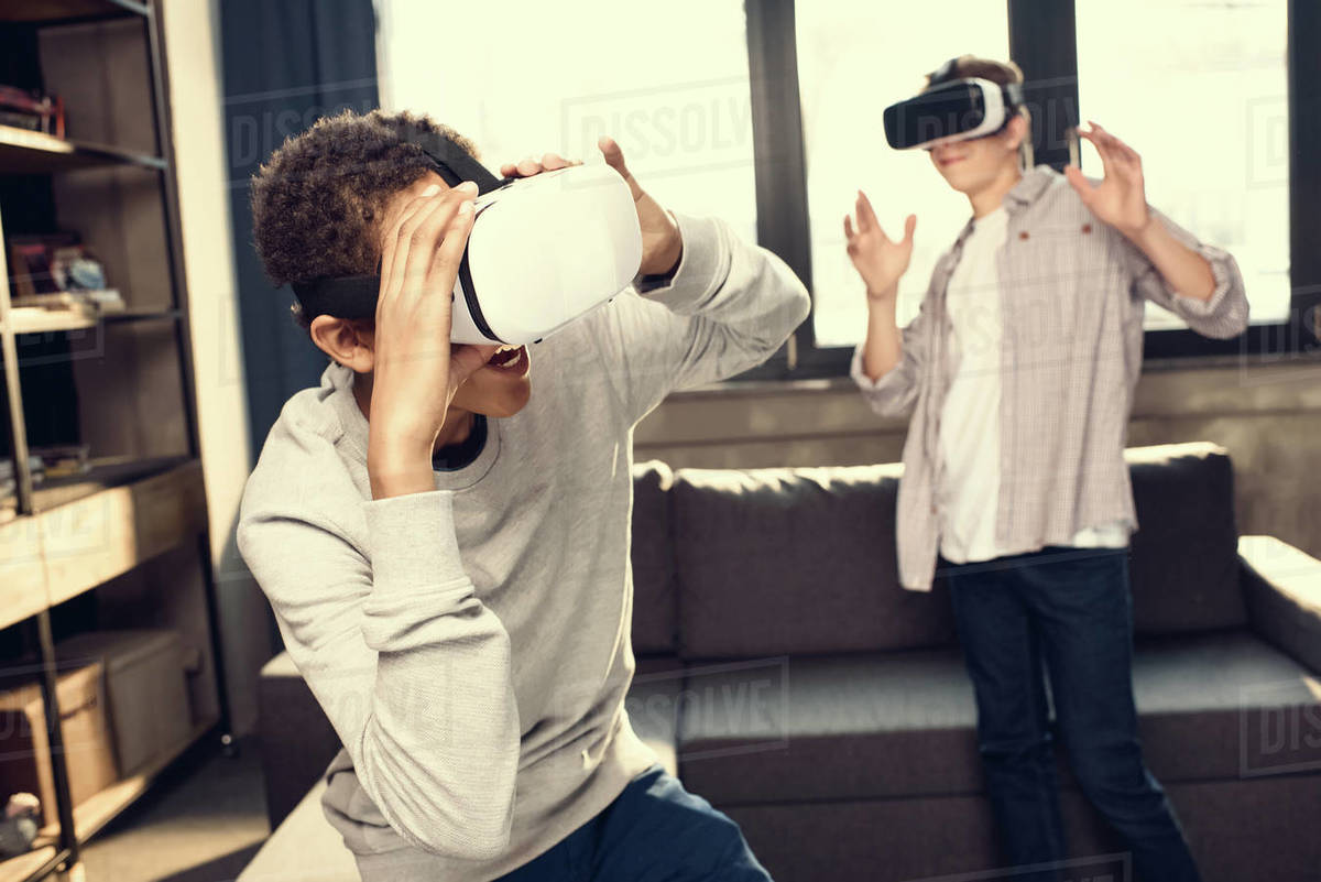 Teenage boys wearing virtual reality headsets at home, teenagers ...